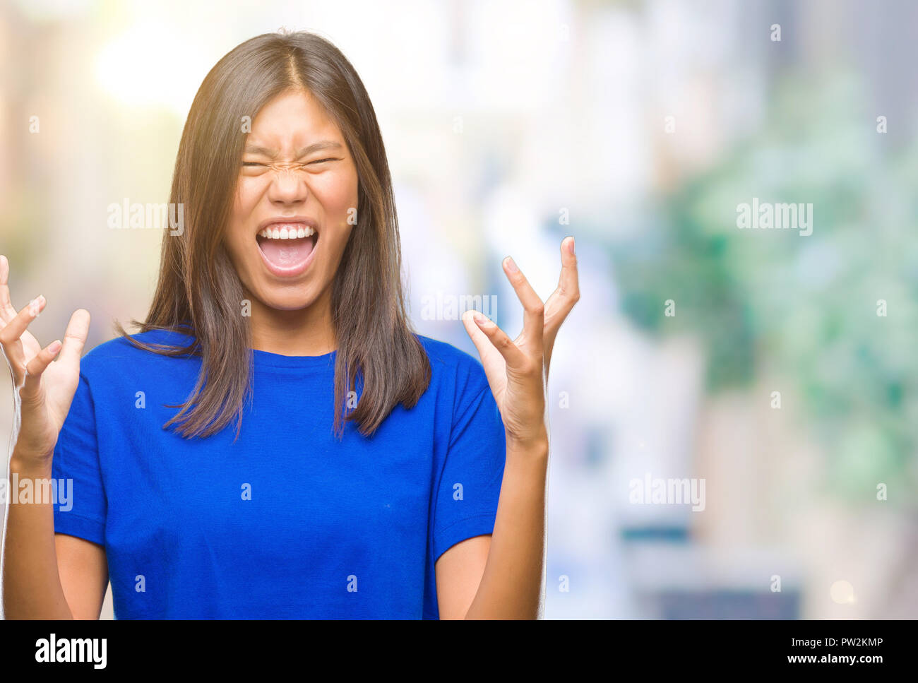 Young asian woman over isolated background crazy and mad shouting and ...
