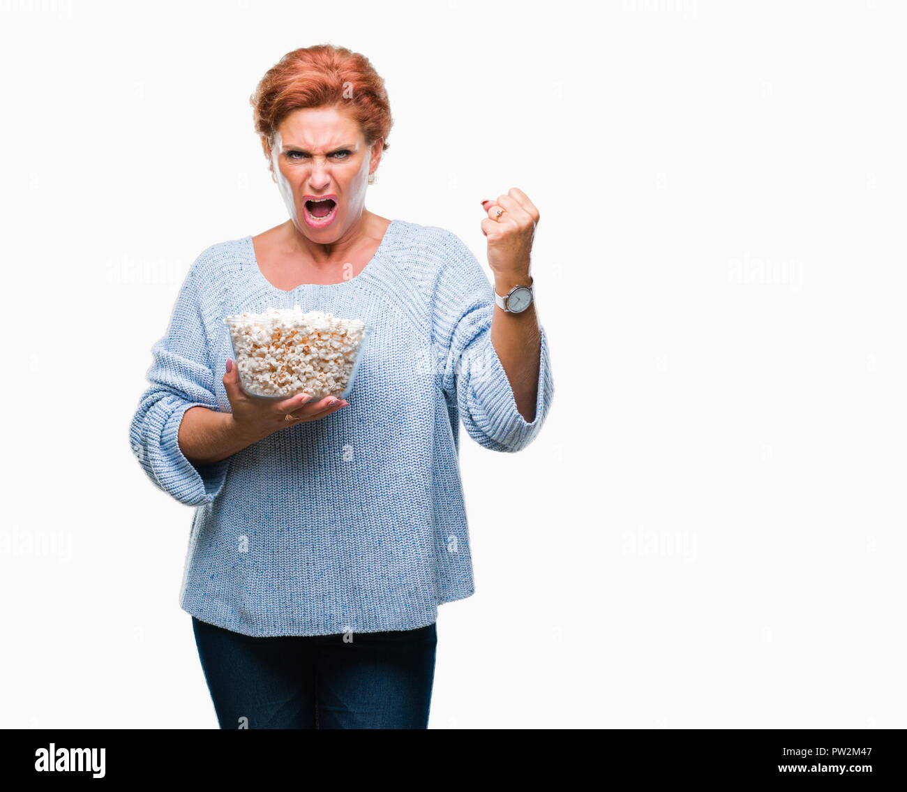 Atrractive senior caucasian redhead woman eating popcorn over isolated ...