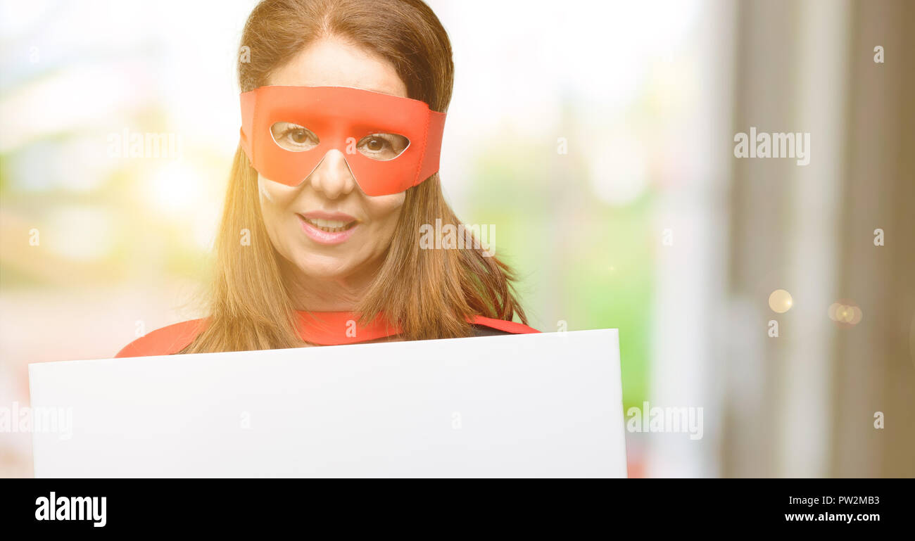 Middle age super hero woman wearing red mask and cape holding blank ...