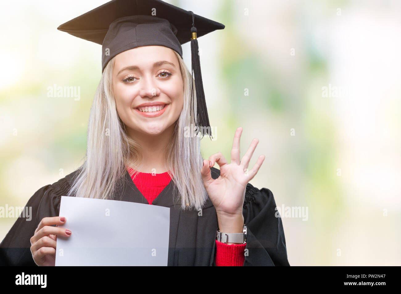 Young blonde woman wearing graduate uniform holding degree over ...