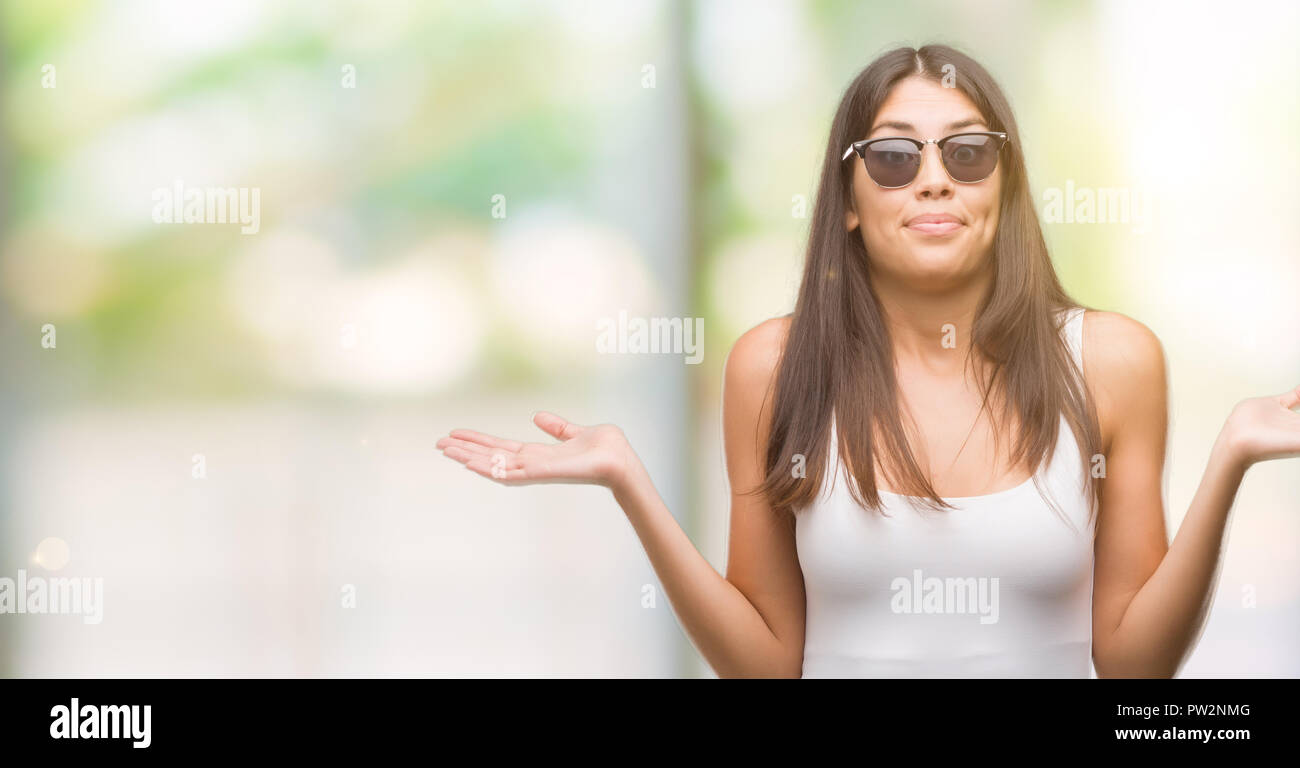 Young beautiful hispanic wearing sunglasses clueless and confused ...
