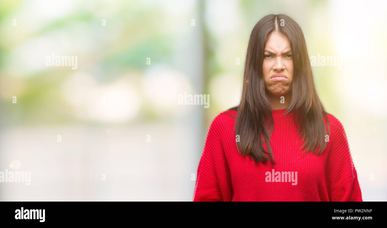 Young beautiful hispanic wearing red sweater depressed and worry for ...