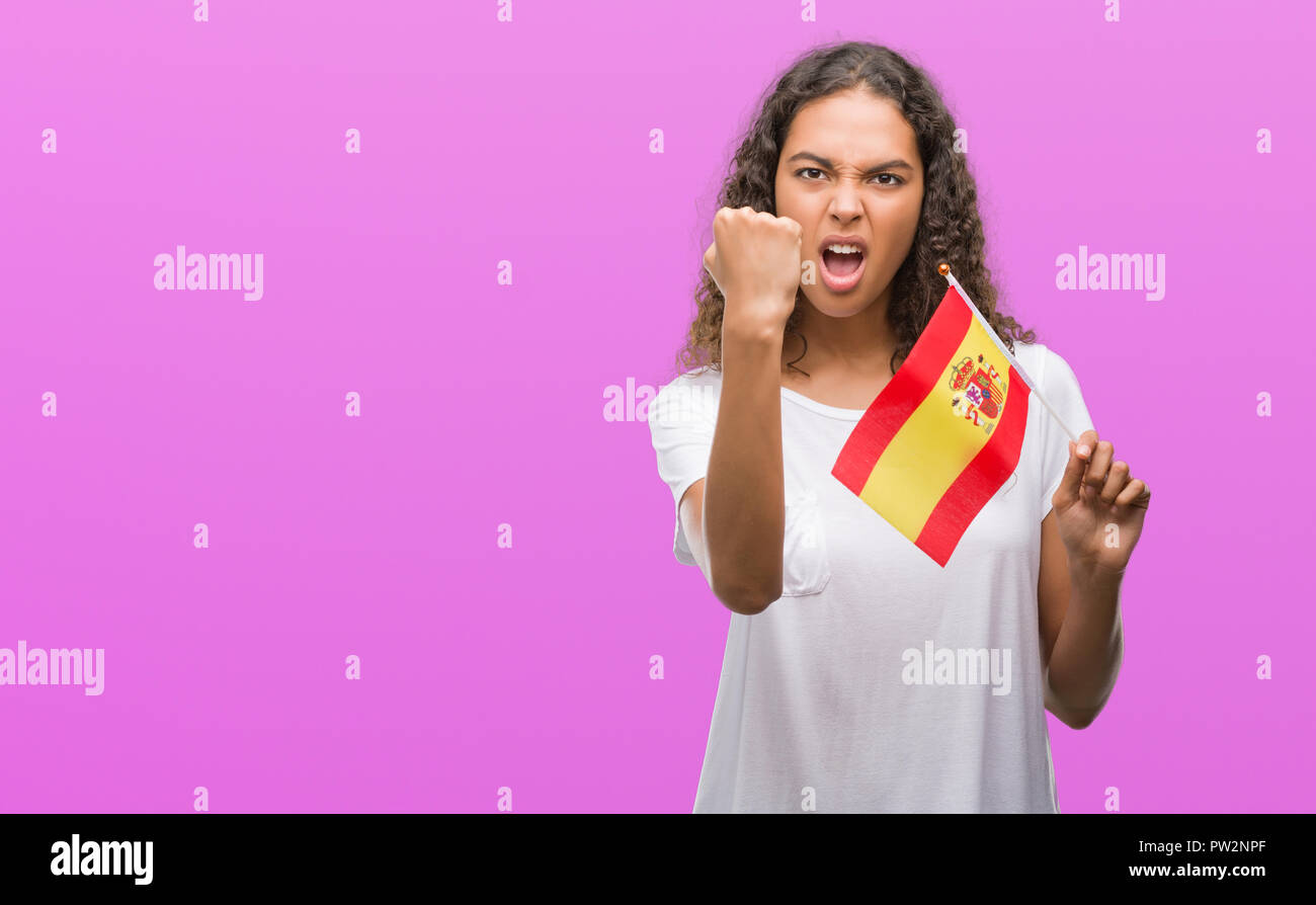 Young hispanic woman holding flag of Spain annoyed and frustrated ...