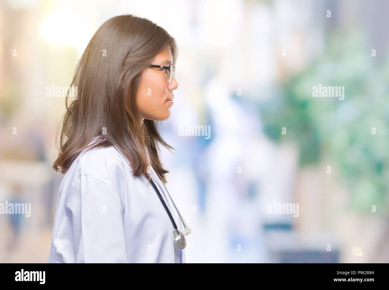Young asian doctor woman over isolated background looking to side ...
