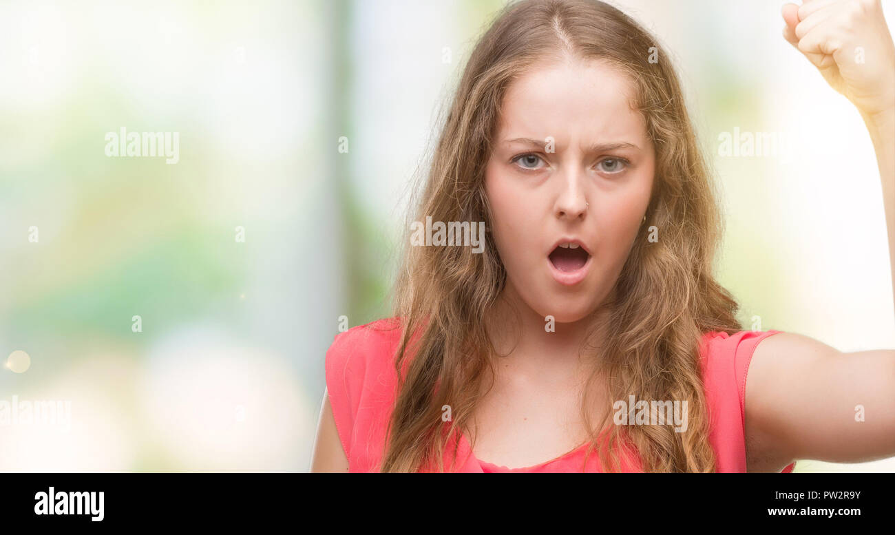 Young blonde woman wearing pink dress annoyed and frustrated shouting ...