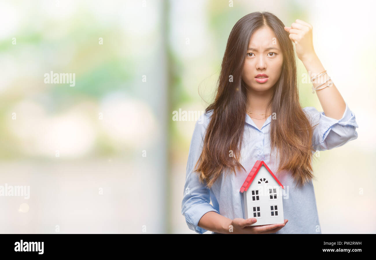 Young asian woman real state agent holding house isolated background ...