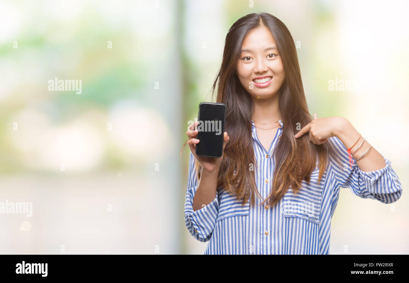 Young asian woman showing blank screen of smartphone over isolated ...
