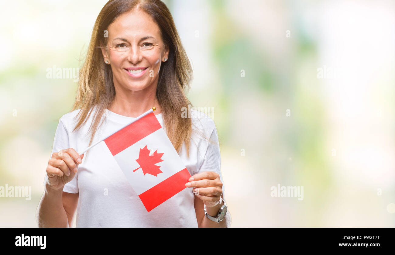 Middle age hispanic woman holding flag of Canada over isolated ...