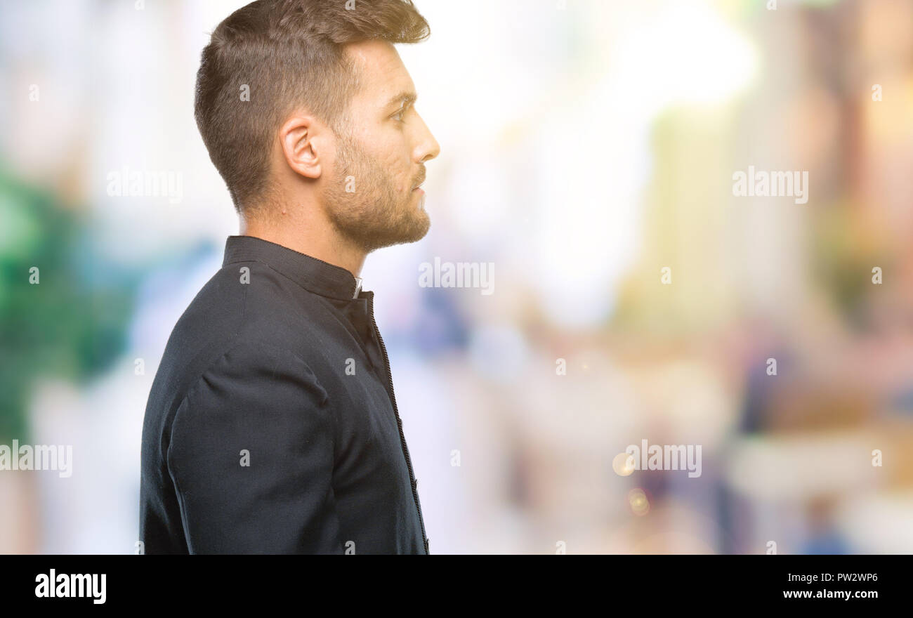 Young catholic christian priest man over isolated background looking to ...