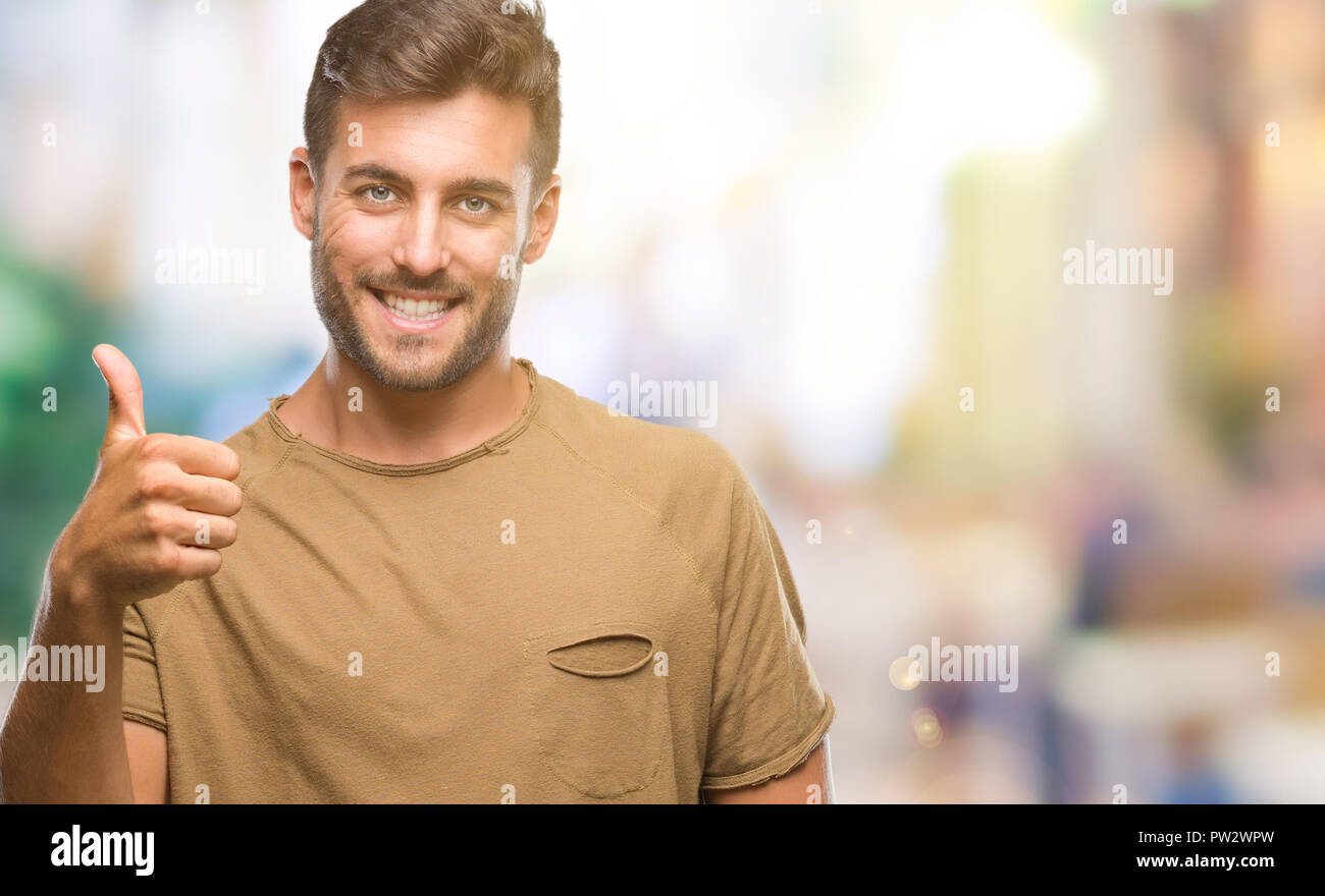 Young handsome man over isolated background doing happy thumbs up ...