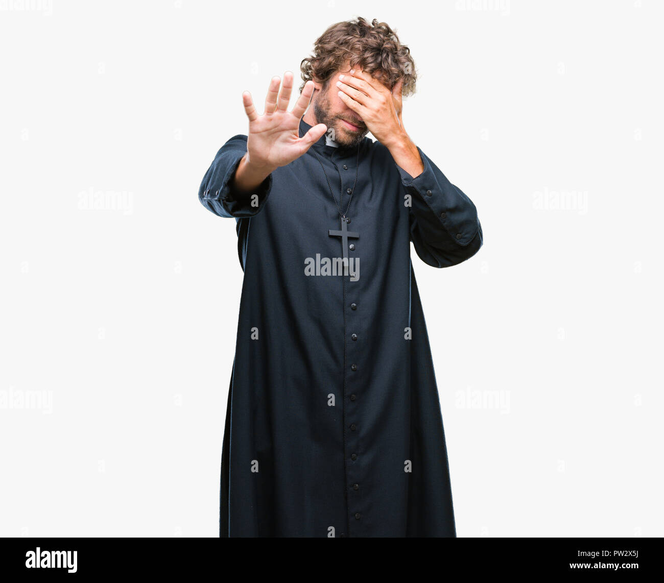 Handsome hispanic catholic priest man over isolated background covering ...