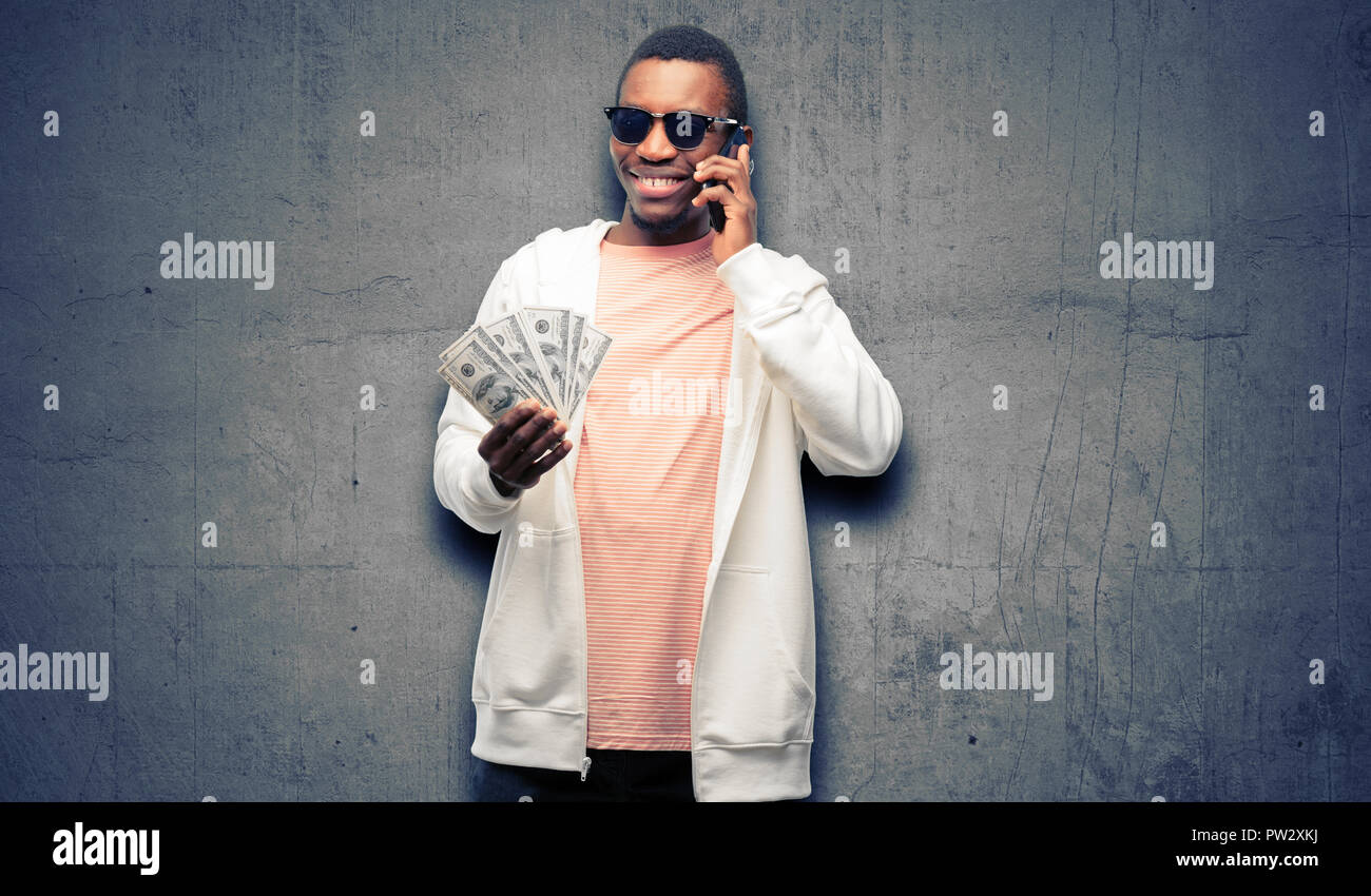 African man holding dollar bank notes happy talking using a smartphone ...