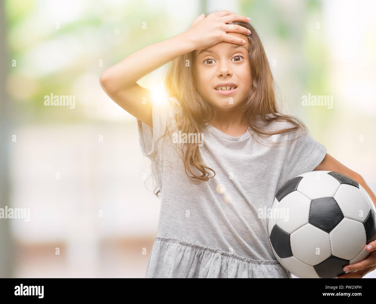 Brunette hispanic girl holding soccer football ball stressed with hand ...