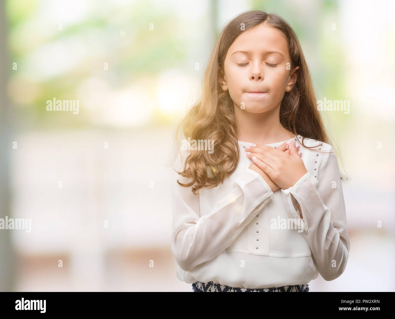 Brunette hispanic girl smiling with hands on chest with closed eyes and ...