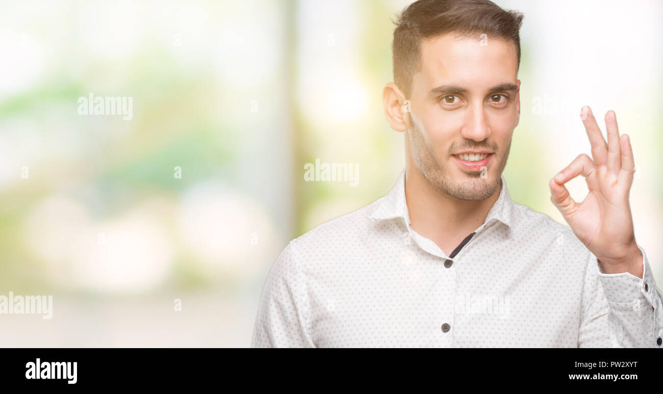 Handsome young business man doing ok sign with fingers, excellent ...