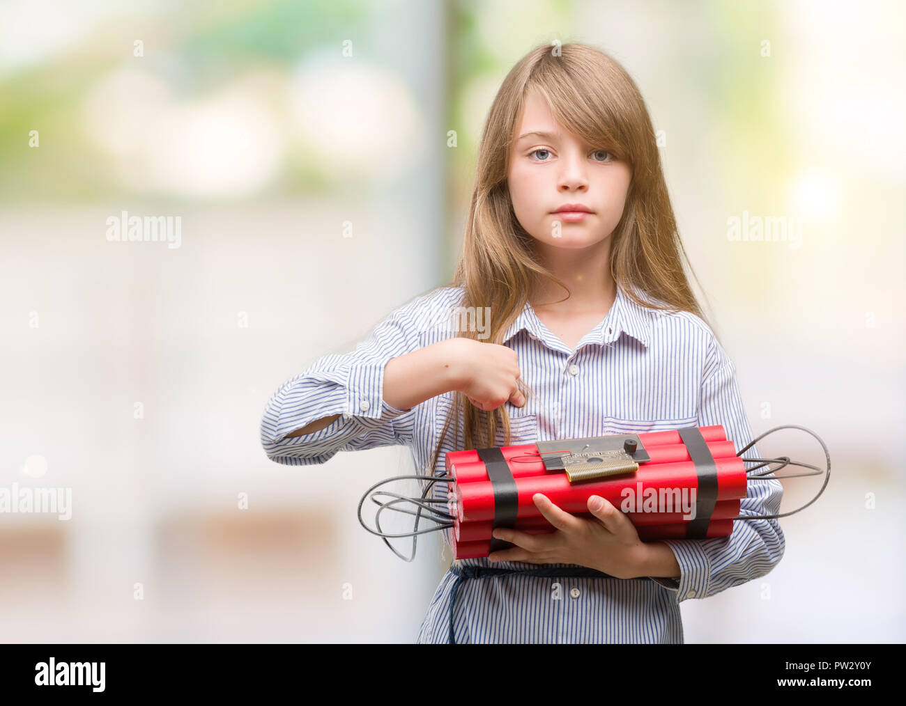 Young blonde child holding dynamite bomb with surprise face pointing ...
