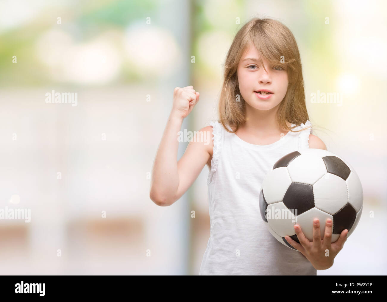 Young blonde toddler holding football ball annoyed and frustrated ...