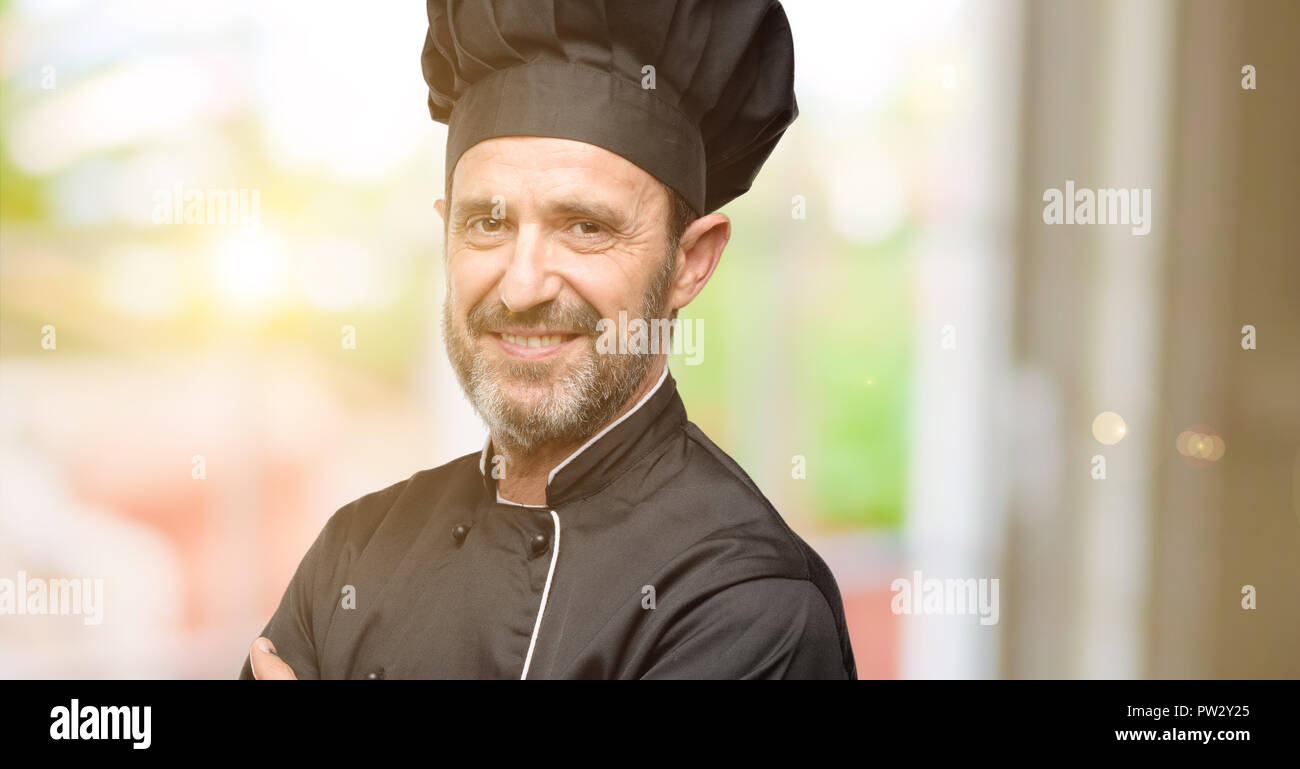 Senior cook man, wearing chef hat with crossed arms confident and happy ...