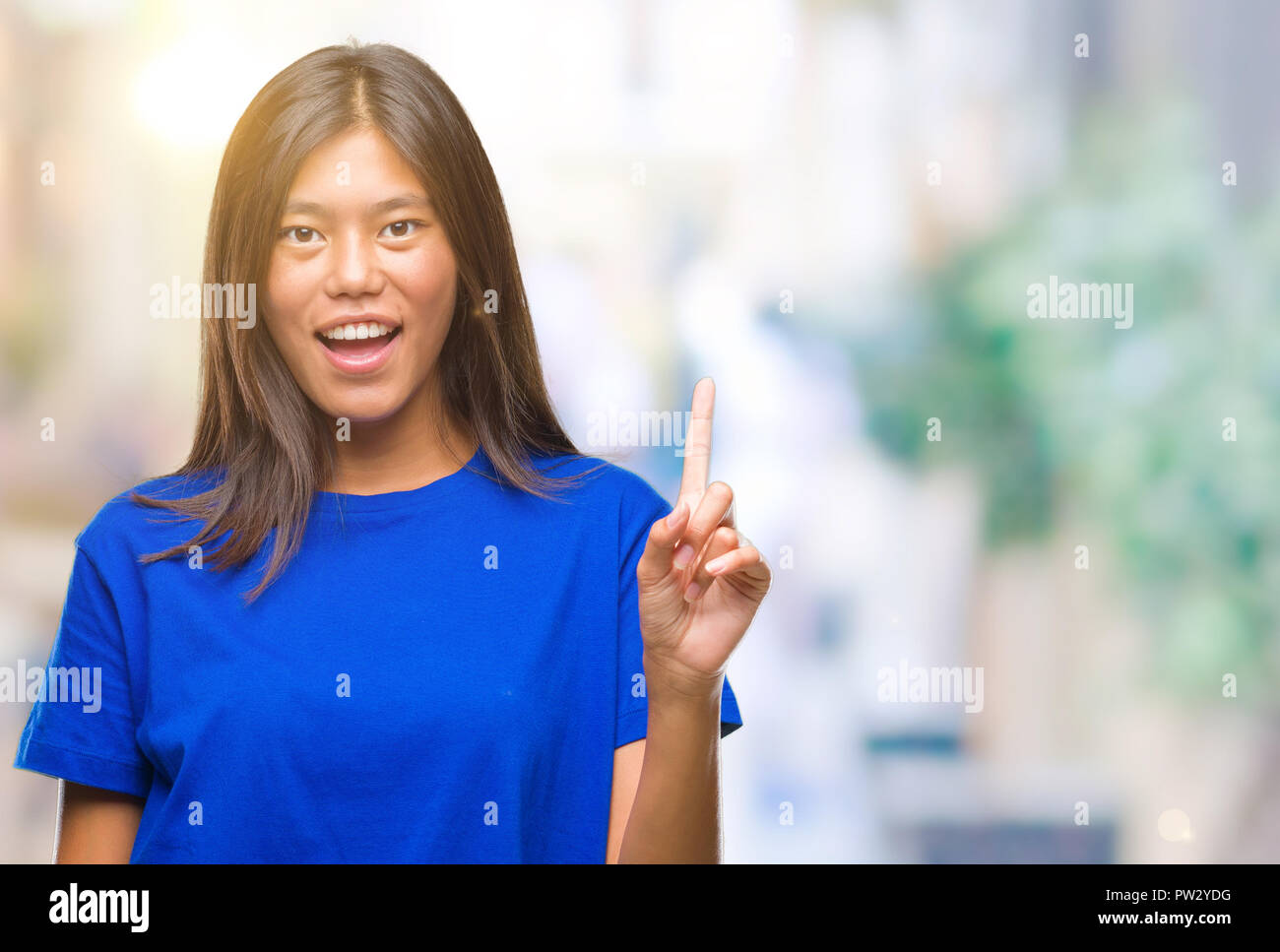 Young asian woman over isolated background showing and pointing up with ...