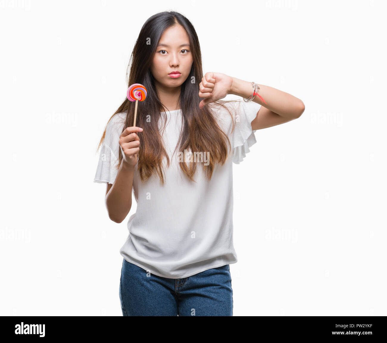 Young asian woman eating lollipop candy over isolated background with ...