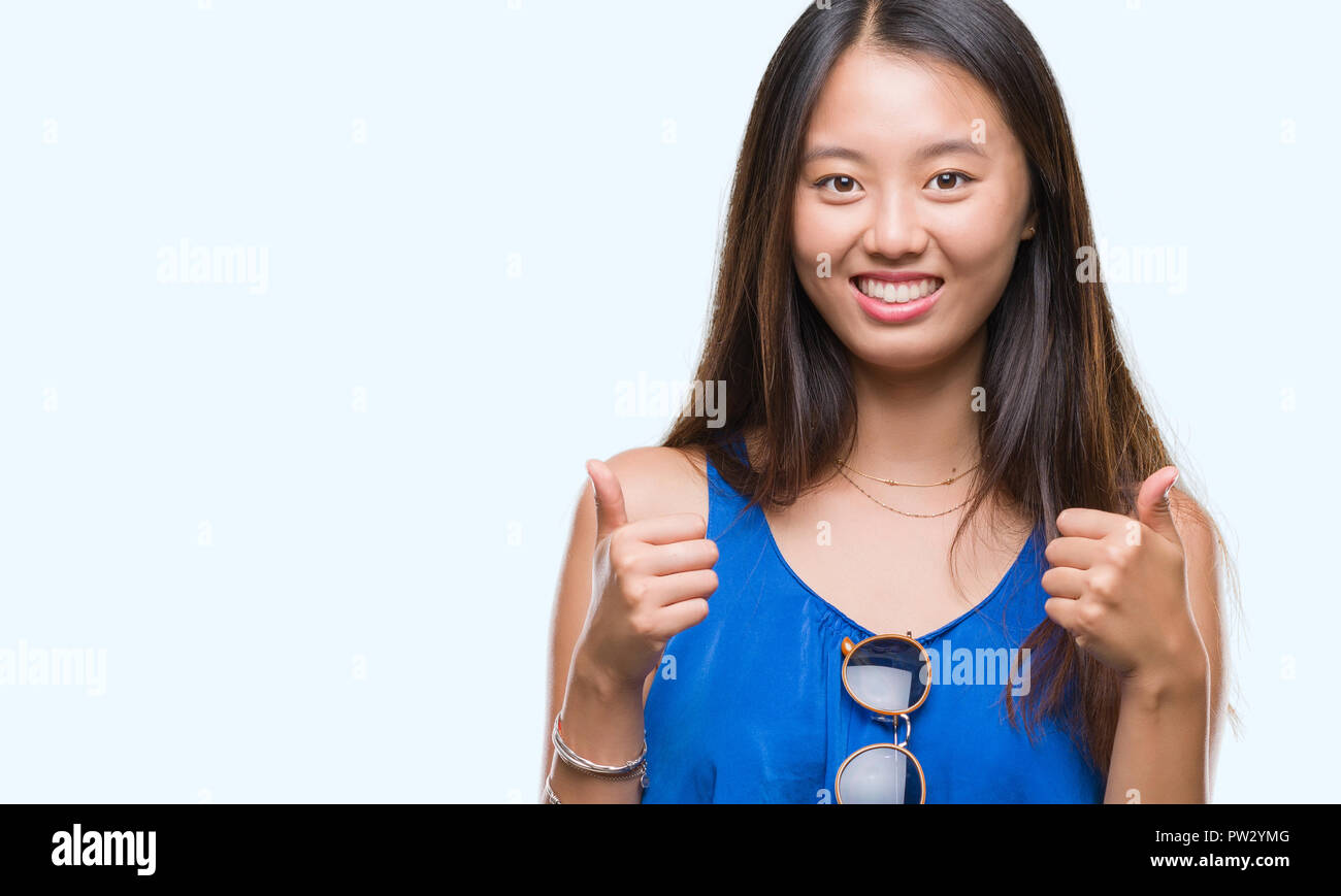 Young asian woman over isolated background success sign doing positive ...