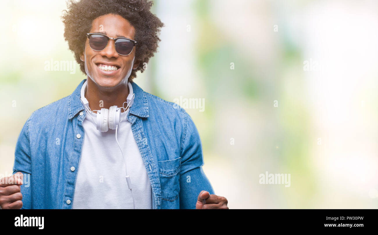 Afro american man wearing headphones listening to music over isolated background very happy and ...
