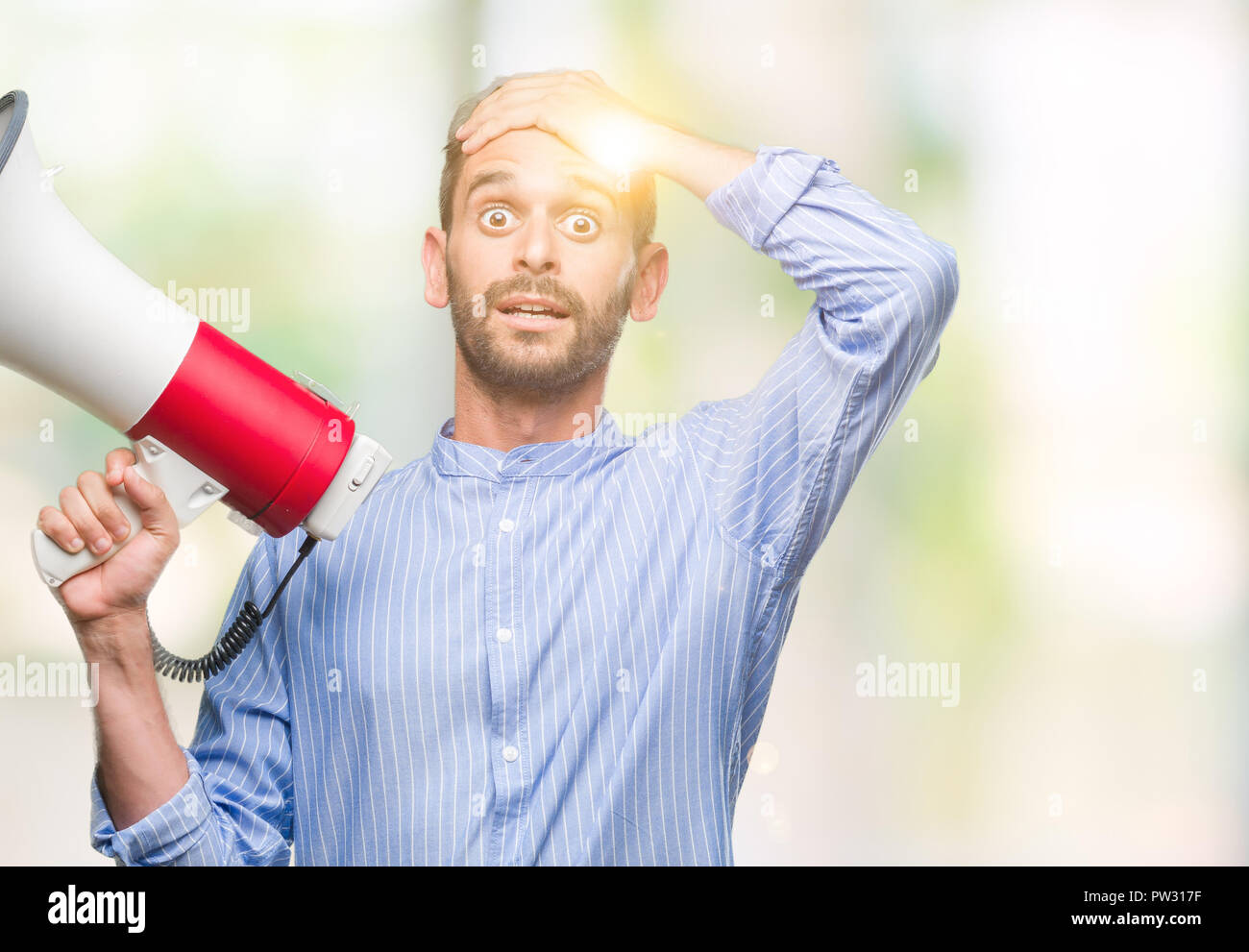 Young handsome man yelling through megaphone over isolated background ...