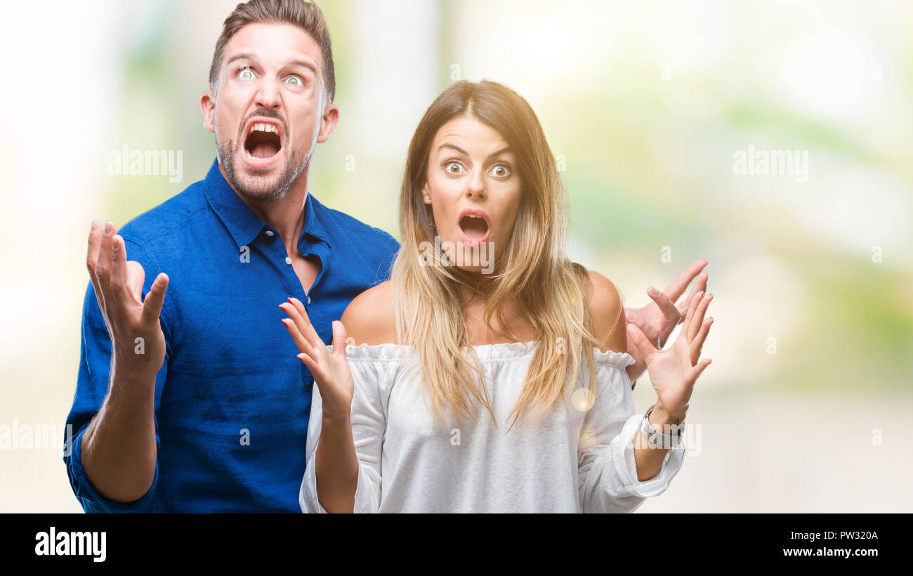 Young couple in love over isolated background crazy and mad shouting ...