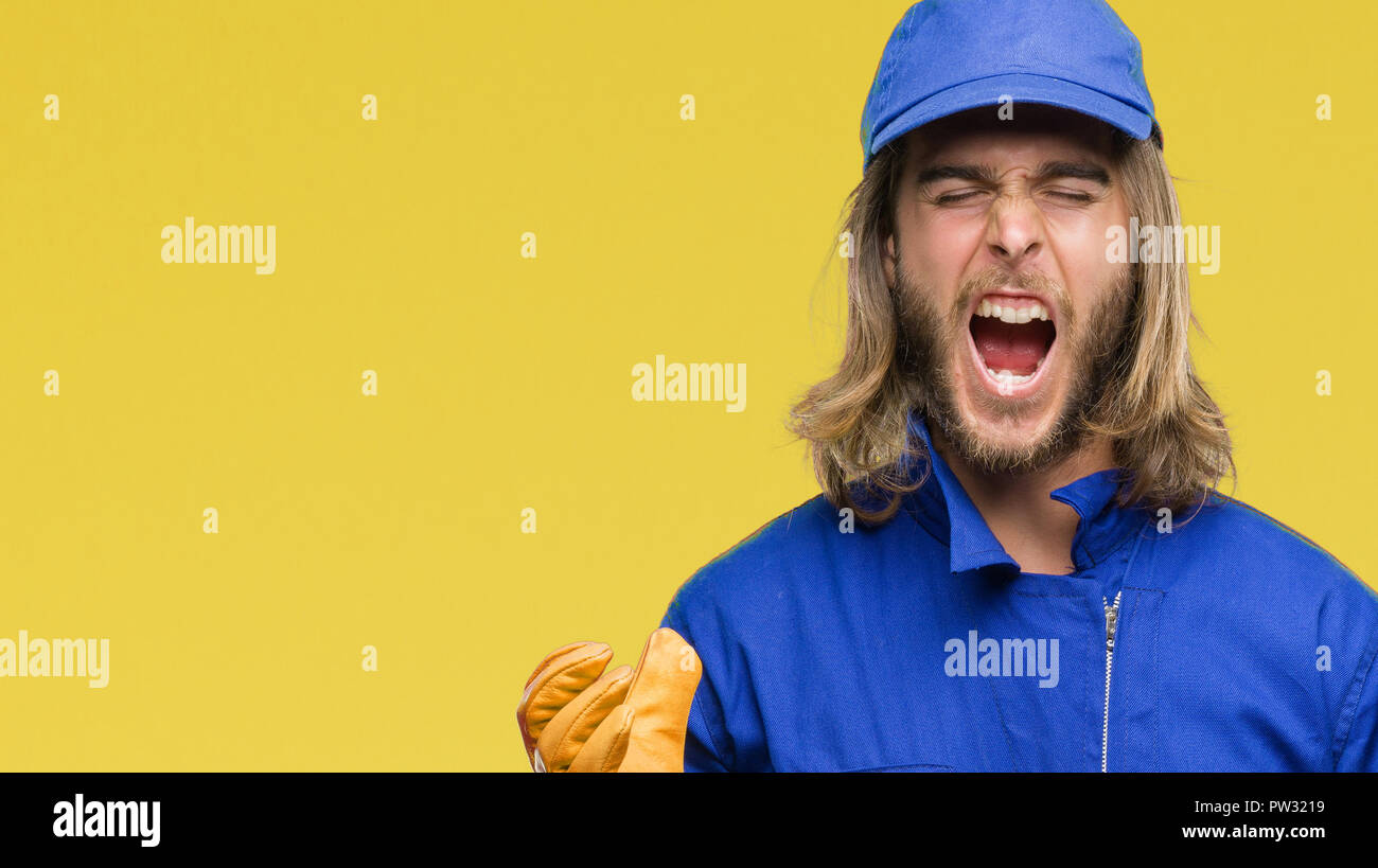 Young handsome mechanic man with long hair over isolated background ...