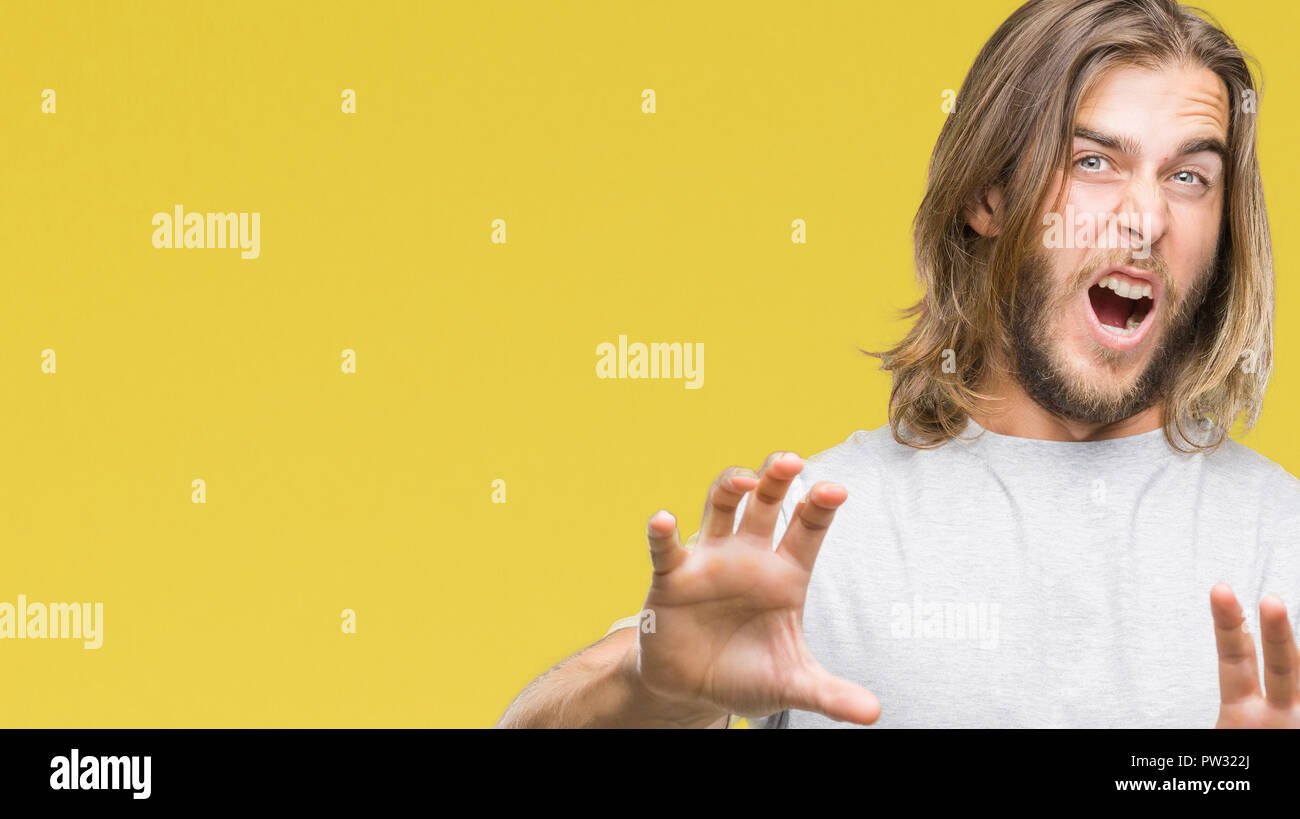 Young handsome man with long hair over isolated background afraid and ...