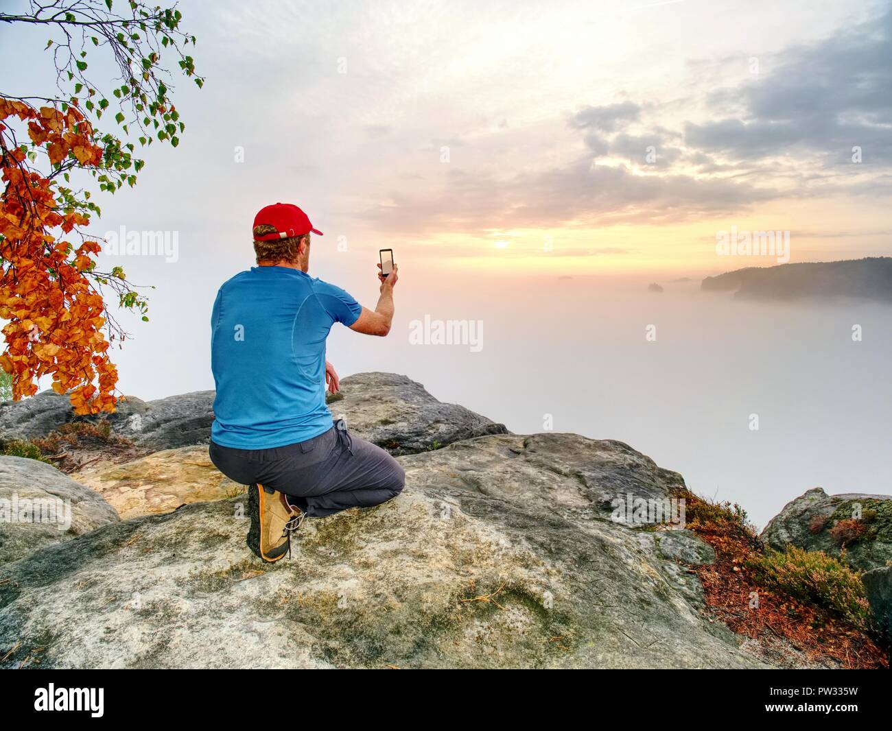 Hiker takes selfie photo, fall nature adventure. Man sit on stone on ...