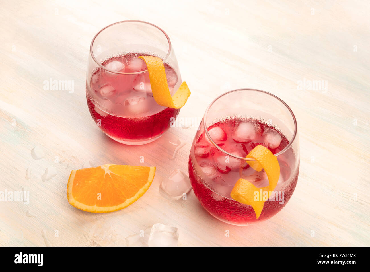 Two vibrant cocktails with campari and orange zest garnishes, with ice ...
