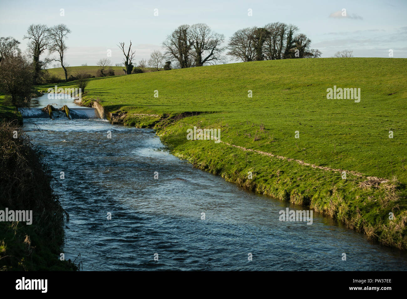 A river runs through green grassy fields near Ratoath, County Meath ...