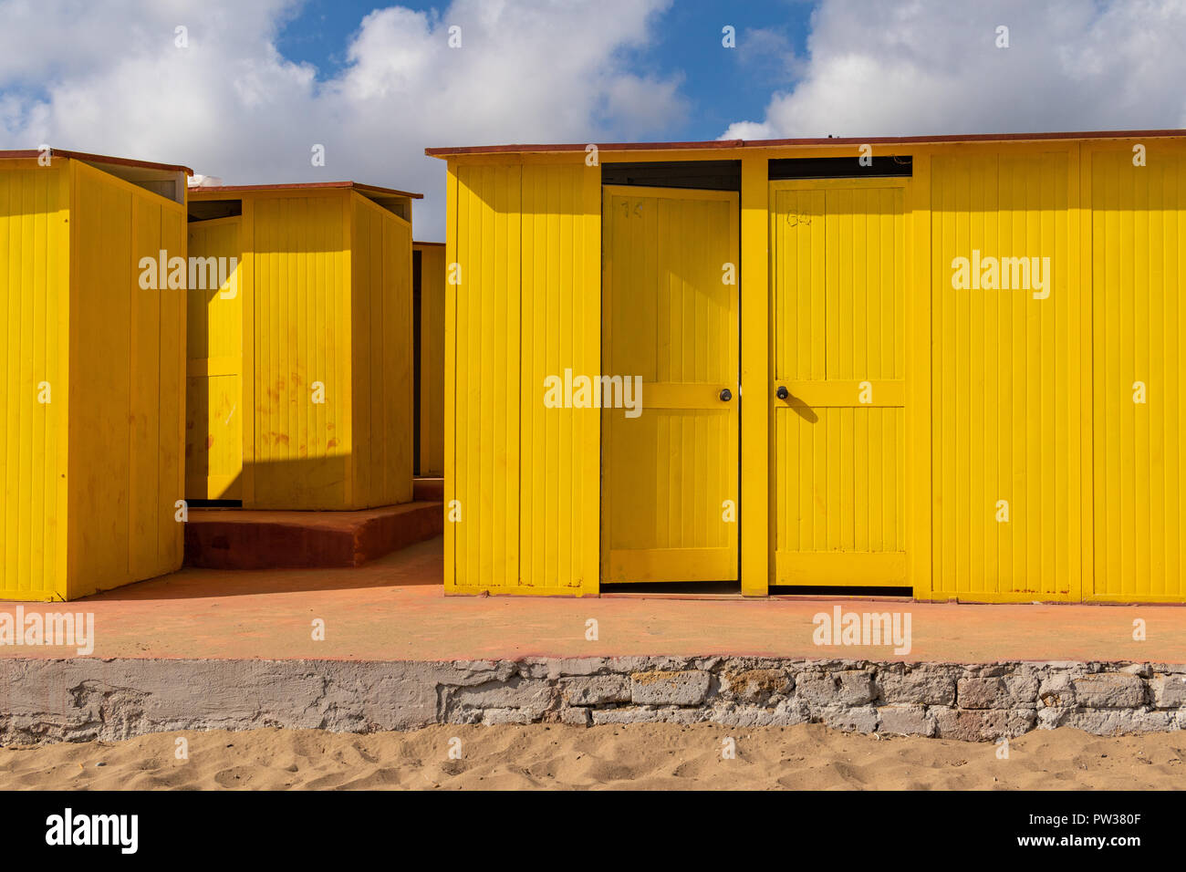 Beautiful yellow Bathing houses on the sandy beach. Empty shelters on a ...
