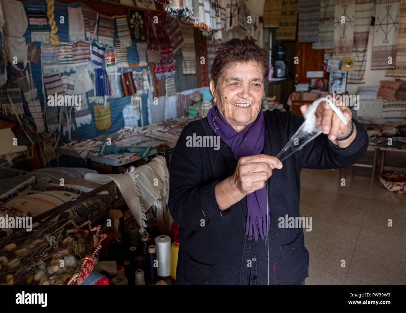 A woman holding cotton and explaining weaving methods at a Museum in ...