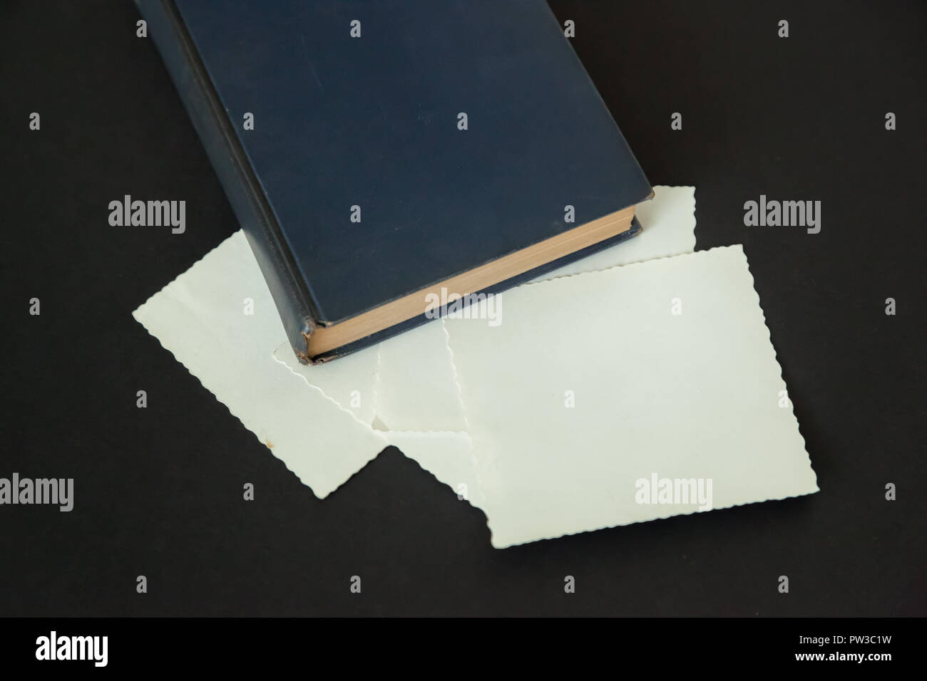 A stack of vintage photos on a black background with a navy blue book ...