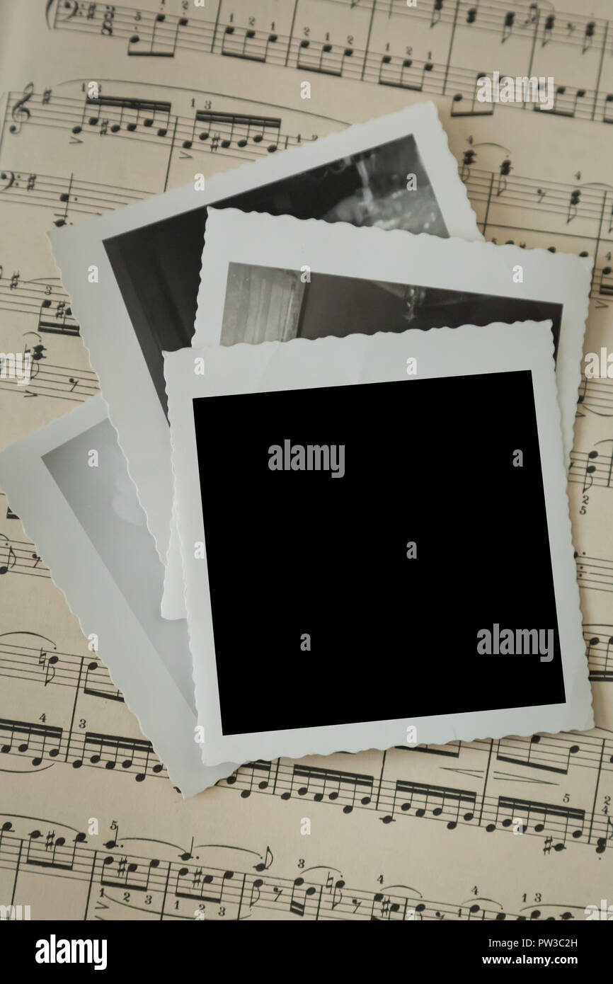 A stack of vintage photos on an old piece of sheet music. Add your own ...