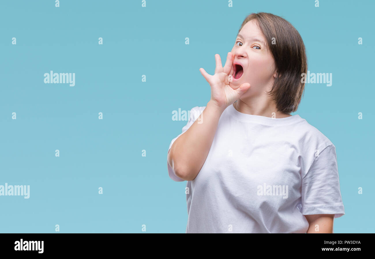 Young adult woman with down syndrome over isolated background shouting ...
