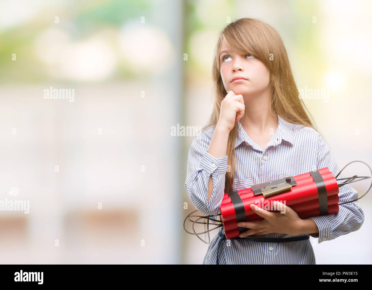 Young blonde child holding dynamite bomb serious face thinking about ...