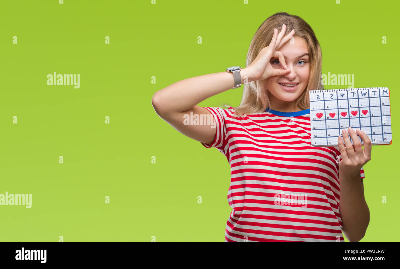 Young caucasian woman holding menstruation calendar over isolated ...