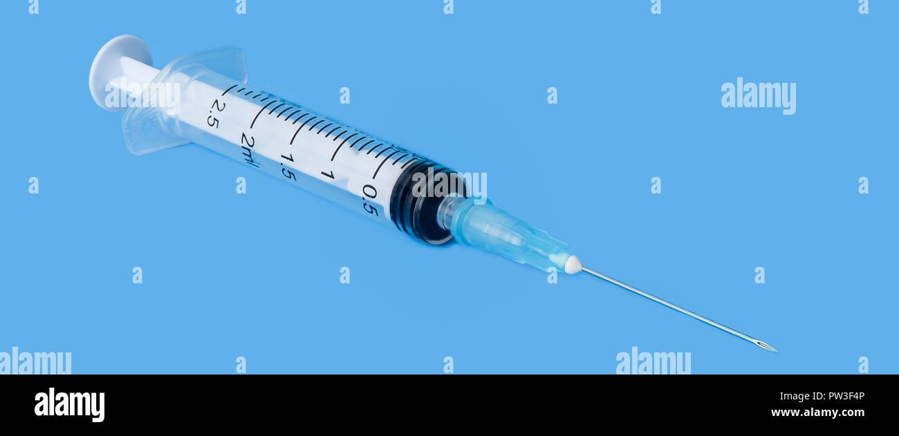 Transparent disposable syringe with a needle on a light blue background ...