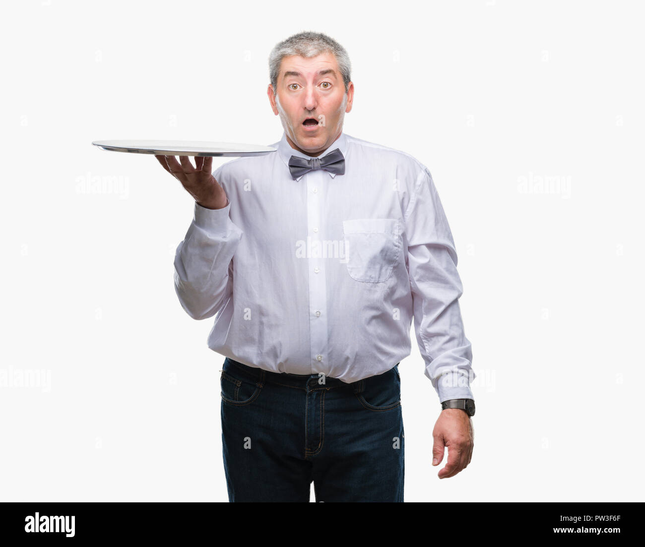 Handsome senior waiter man holding silver tray over isolated background ...