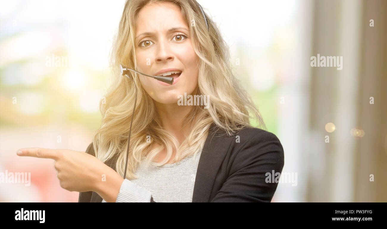 Young woman operator from call center pointing away side with finger ...