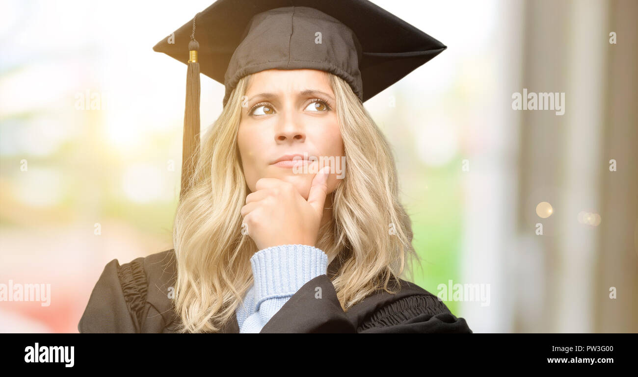 Young graduate woman thinking and looking up expressing doubt and ...