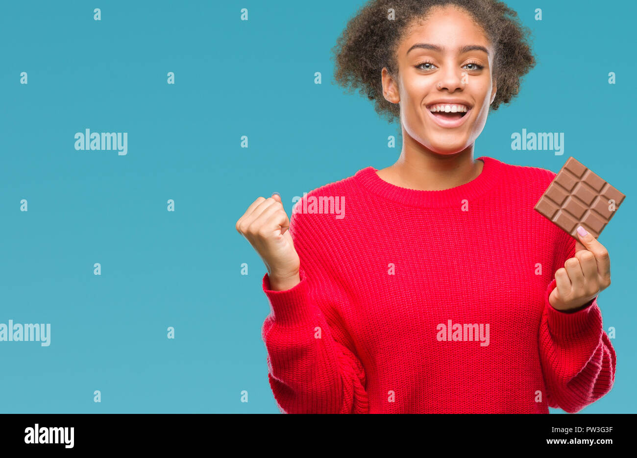 Young afro american woman eating chocolate bar over isolated background ...