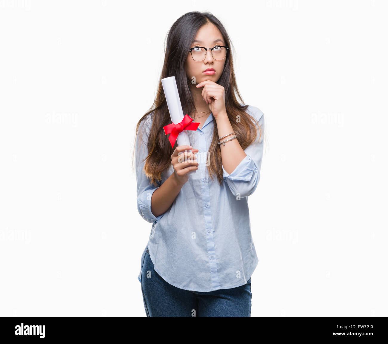 Young asian woman holding degree over isolated background serious face ...