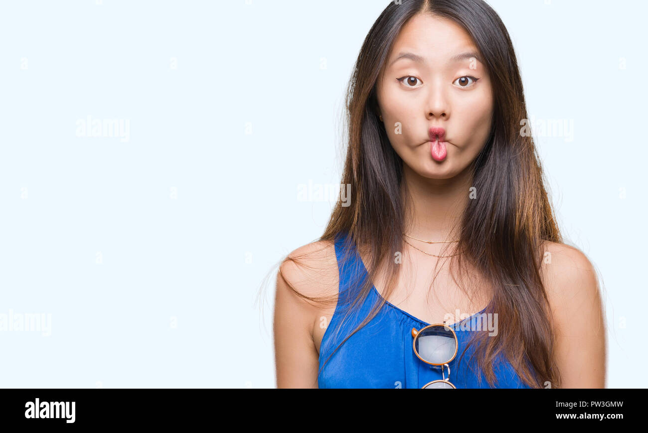 Young asian woman over isolated background making fish face with lips ...