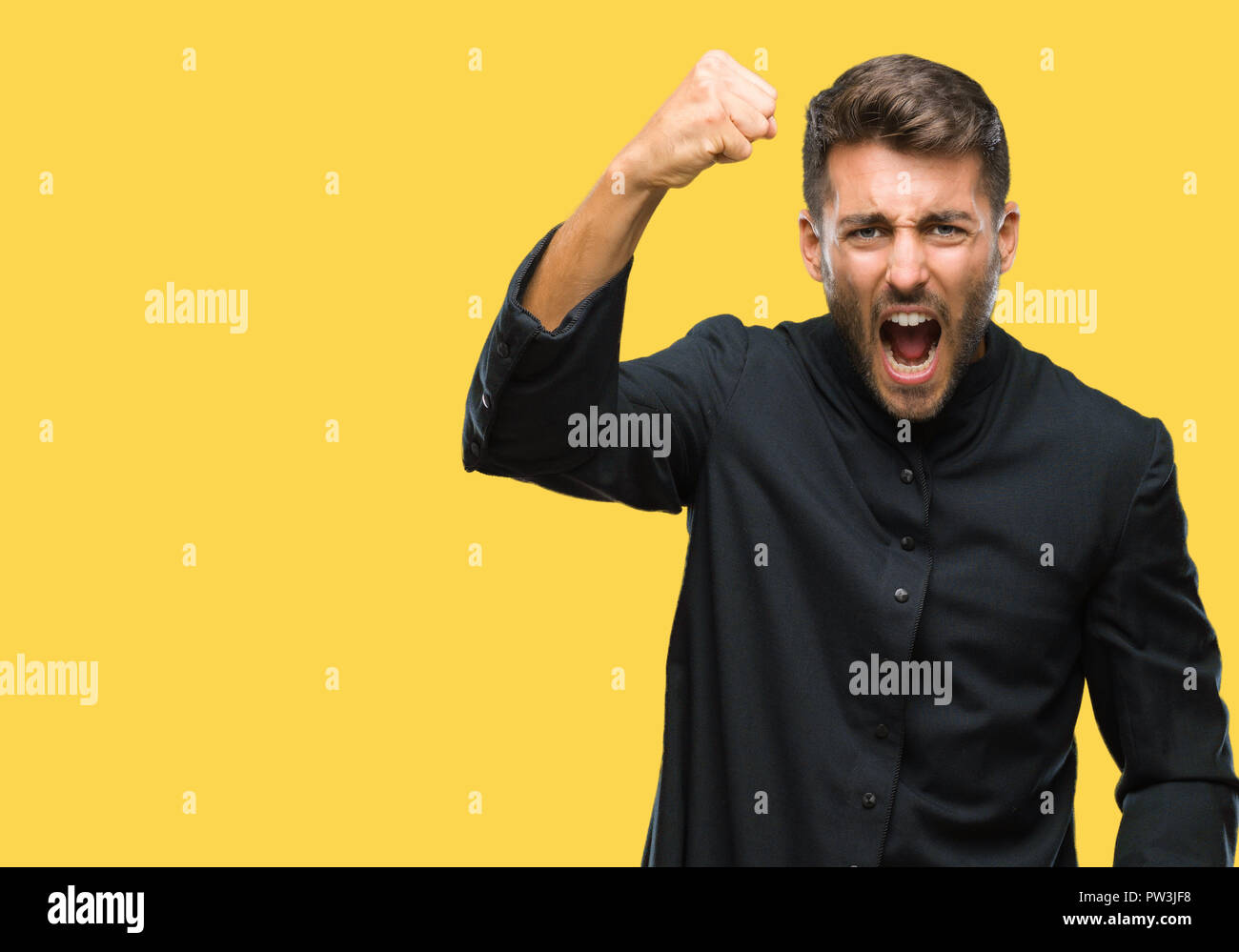 Young catholic christian priest man over isolated background angry and ...