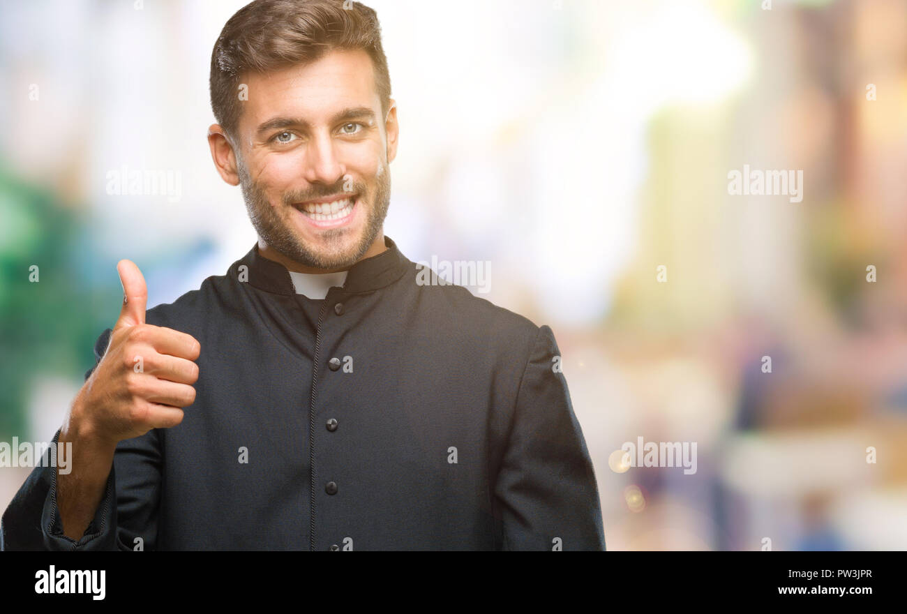 Young catholic christian priest man over isolated background doing ...