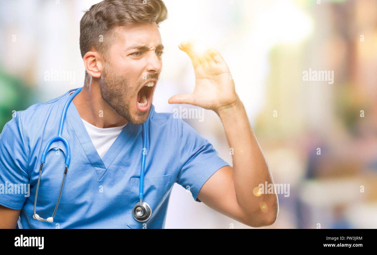 Young handsome doctor surgeon man over isolated background shouting and ...